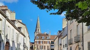 Rua de calçada com edifícios históricos, uma torre de igreja imponente e uma bicicleta estacionada à direita.