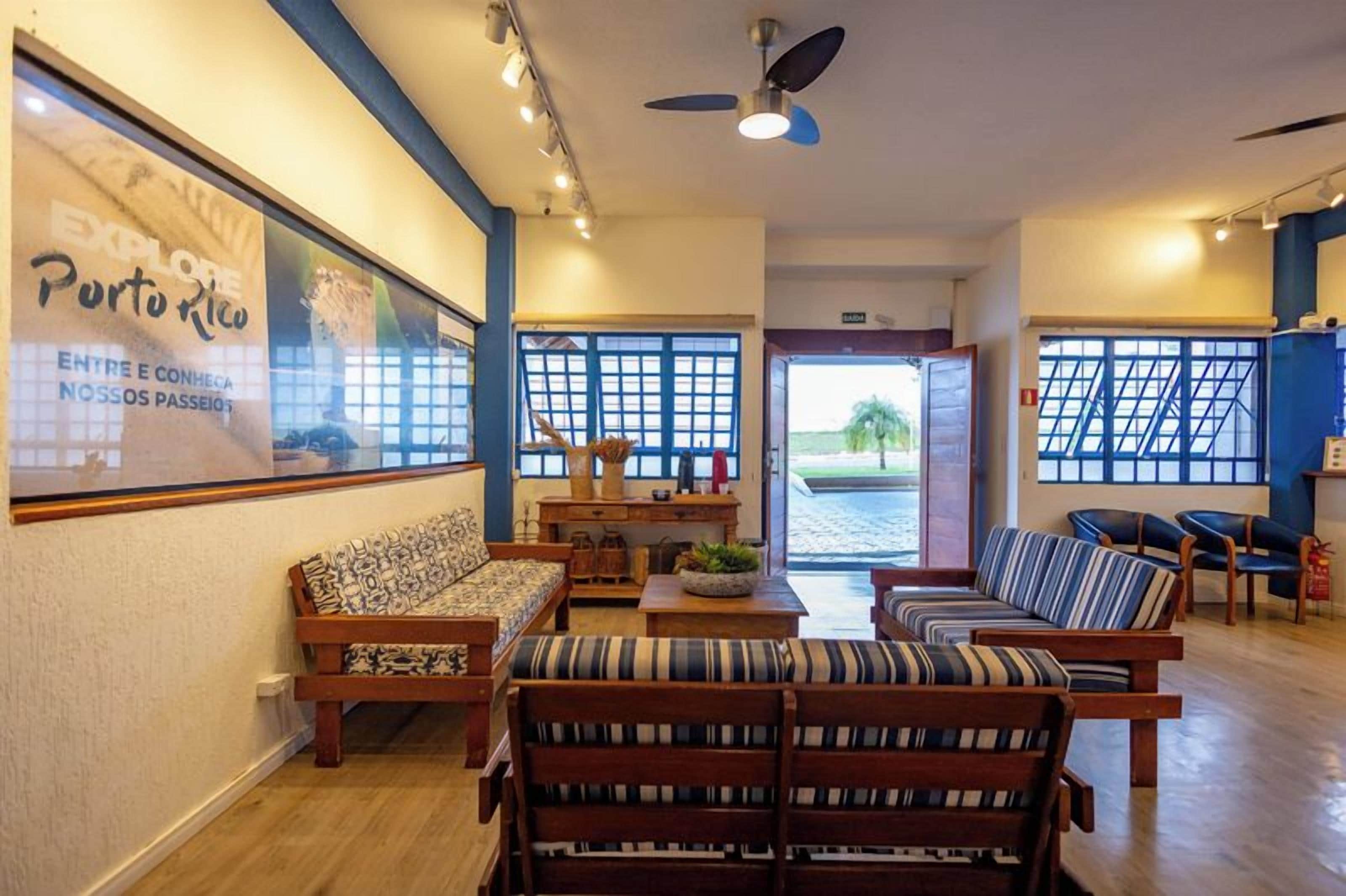Um saguão de hotel com um conjunto de sofás, uma mesa de centro e vista para o exterior.