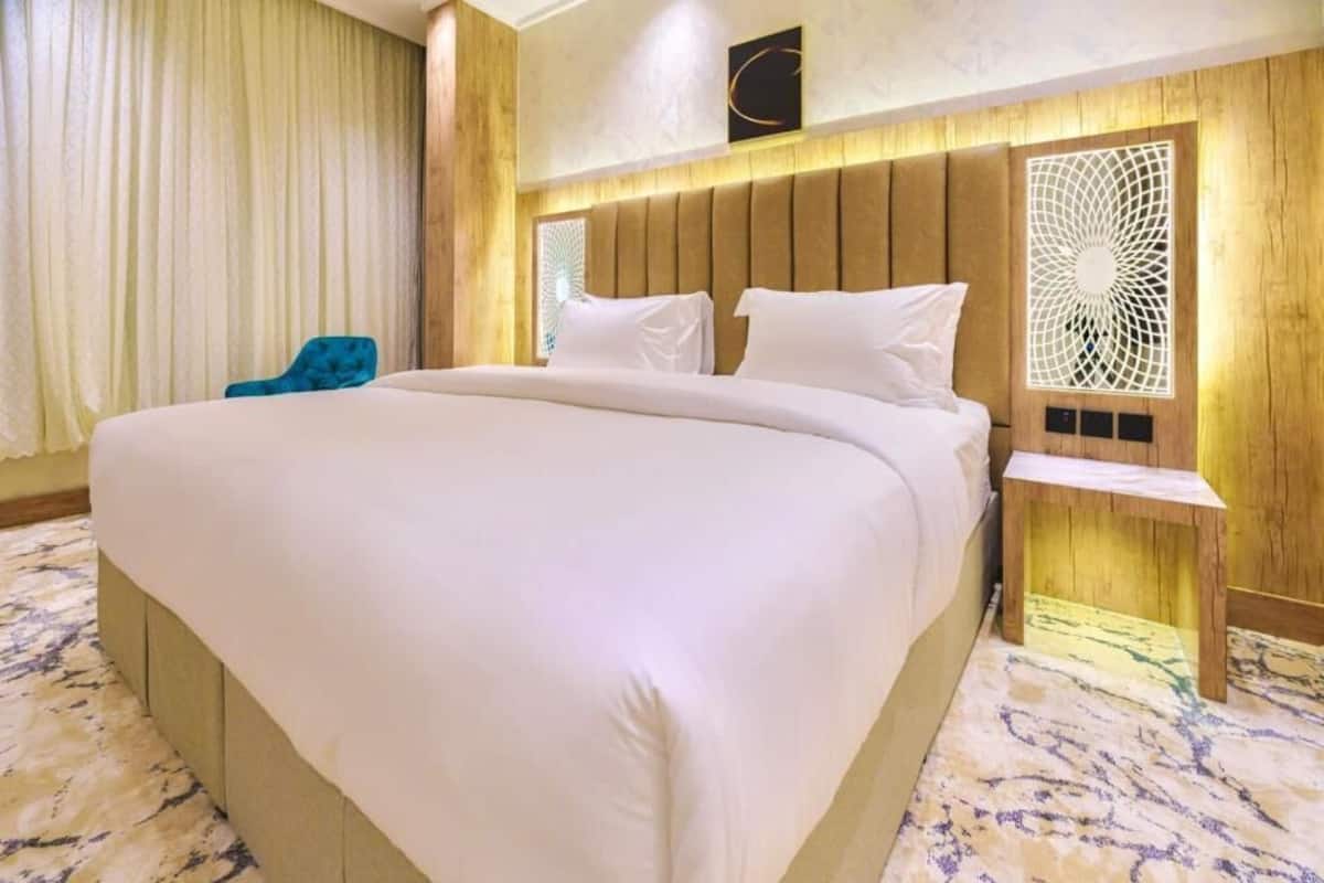 Uma cama grande com cabeceira de madeira, mesa de cabeceira e um painel decorativo na parede.