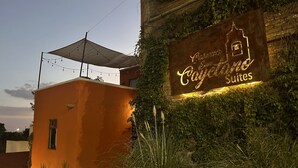 Um edifício com uma placa para "Ouzel Suites" parcialmente coberto por hera.