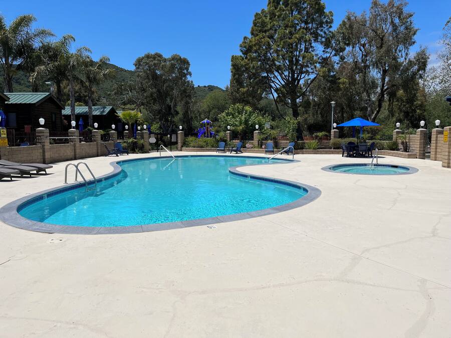 Uma área de piscina com várias piscinas, espreguiçadeiras e guarda-sóis.