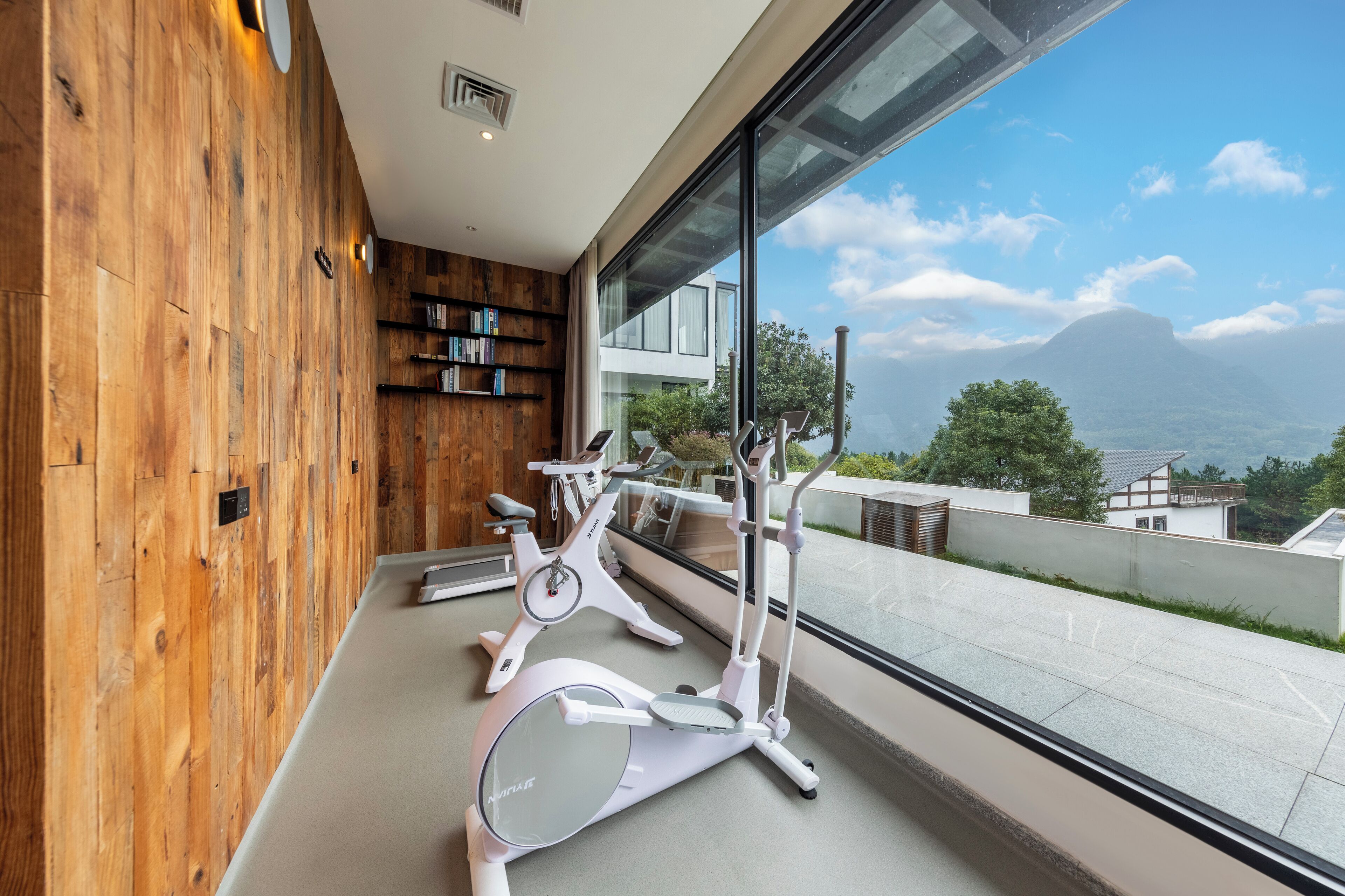 Quarto moderno com paredes de madeira, uma janela grande e equipamentos de ginástica.