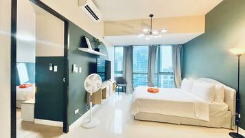 Quarto de hotel moderno com uma cama grande, uma escrivaninha com cadeira, uma televisão e vista para a cidade.