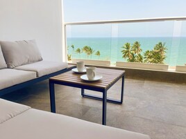 Varanda com vista para o oceano, um sofá e uma mesa com duas chávenas.