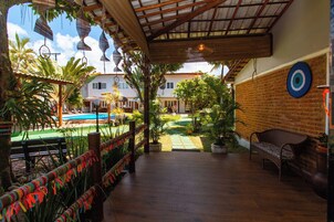 Área de varanda coberta com piscina, plantas em vasos e um muro de tijolos com decoração em alvo.