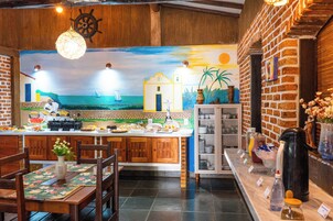Restaurante com mural temático náutico, mobiliário de madeira e sistema de buffet.