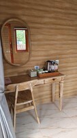Uma escrivaninha de madeira com um espelho, uma pequena janela e um tabuleiro com artigos de higiene pessoal.