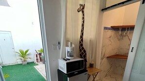 Quarto compacto com mini-geladeira, cafeteira e decoração com girafa.