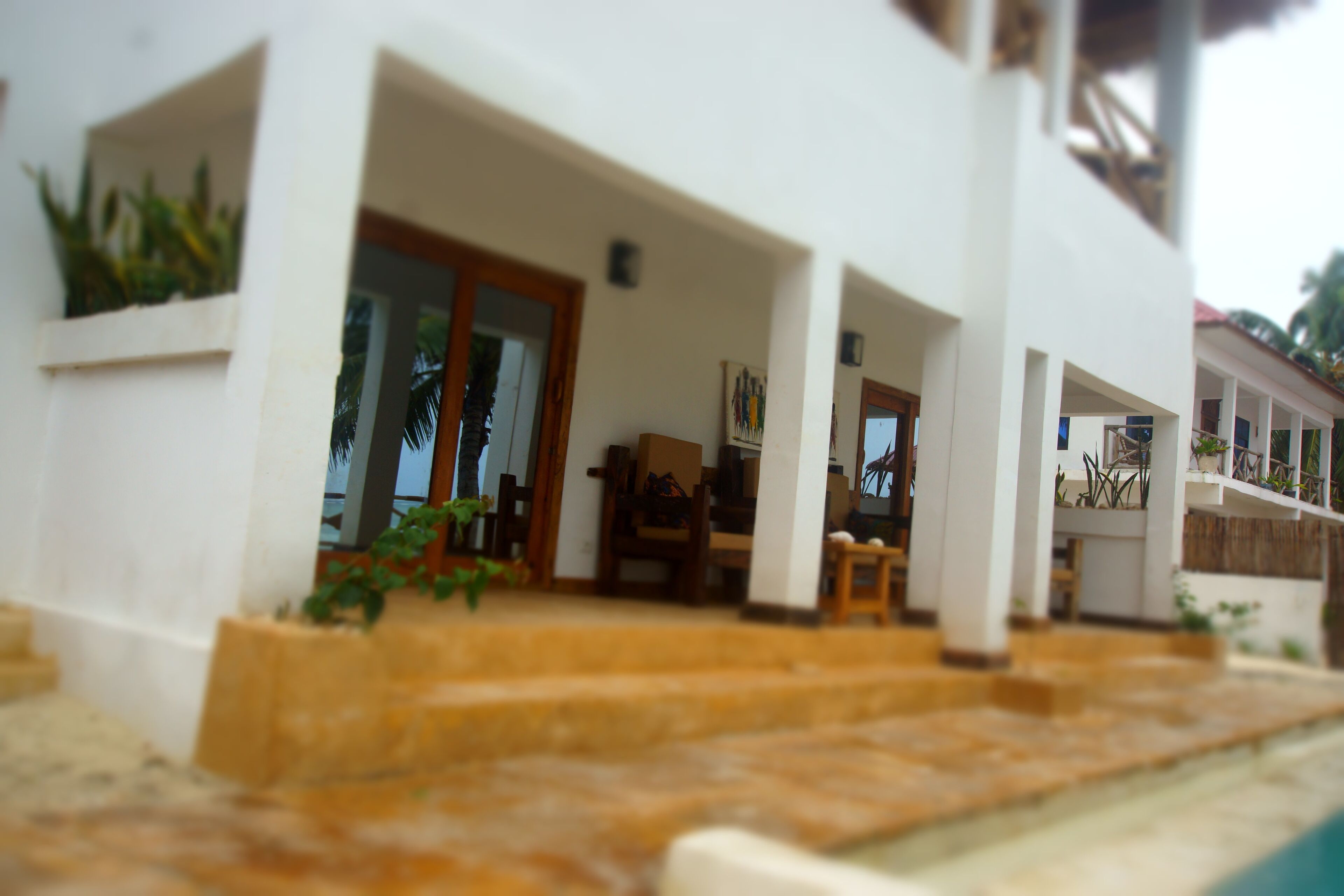 Uma casa moderna com varanda coberta, piscina e escadaria que leva à entrada.