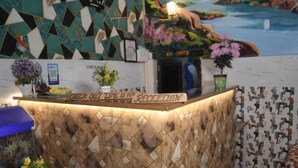 Uma área de recepção com balcão de check-in, um mural na parede e piso de azulejos.