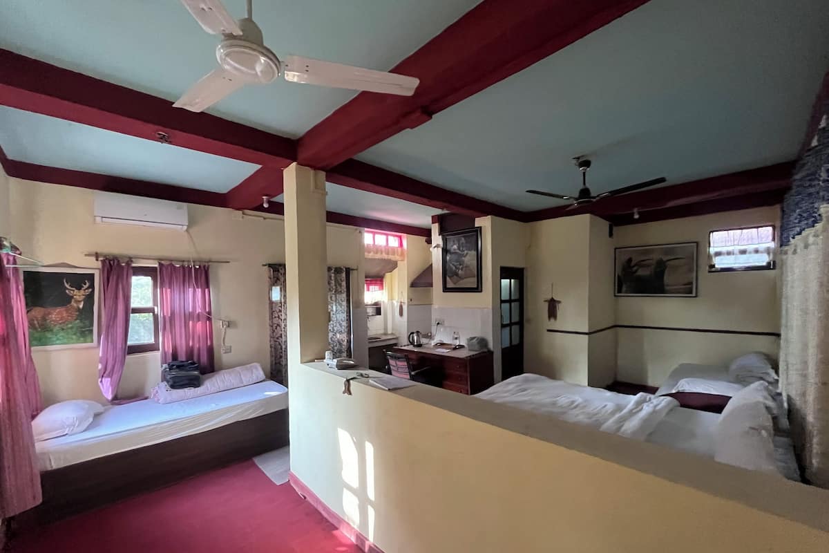 Quarto com cama, escrivaninha, cadeira, ventoinha no teto e janela com cortinas.