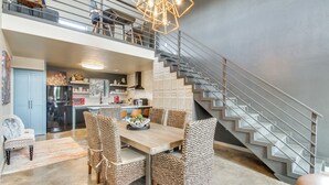 Cozinha moderna com área de jantar, com escada e vista para a sala de estar.