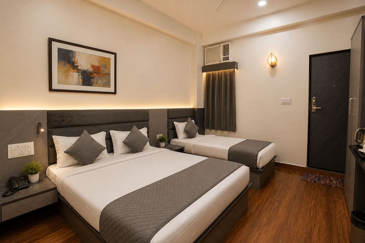 Quarto de hotel com duas camas, um quadro na parede, ar condicionado e uma porta.