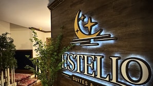 Uma placa de madeira com o nome "ESTELLO SUITES & SPA" e uma lua crescente com estrelas.