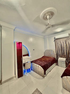 Quarto com cama, escrivaninha, cadeira e ventoinha no teto.
