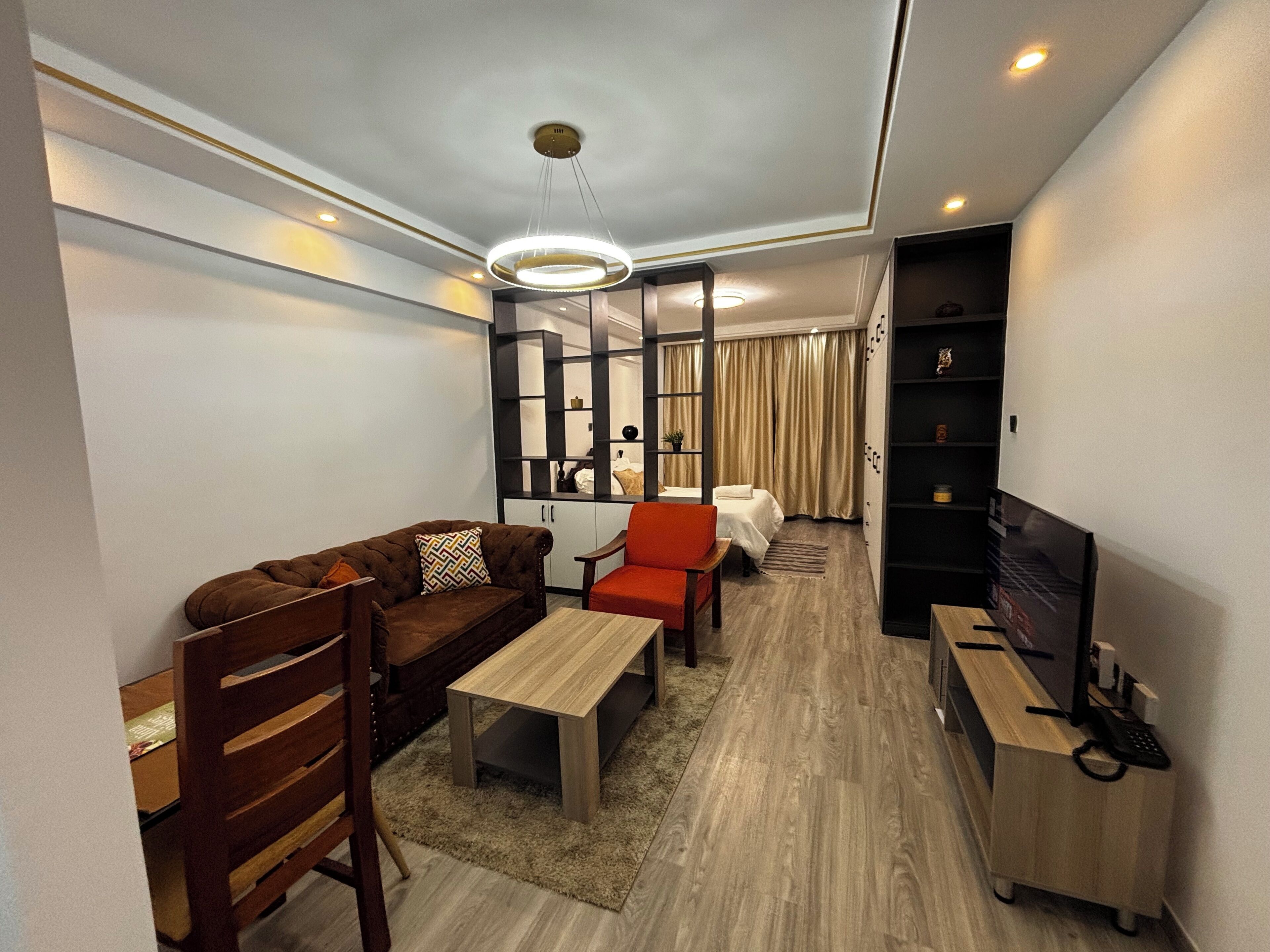 Uma sala de estar moderna com sofá, poltrona, mesa de centro, rack para TV e estante.