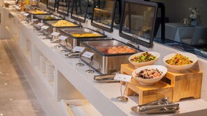 Buffet com diversos pontos de comida, incluindo uma barra de saladas e um espaço com carnes.