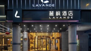 Entrada de hotel com porta giratória, um destaque para o letreiro 'LAVANDE' e design arquitetônico moderno.