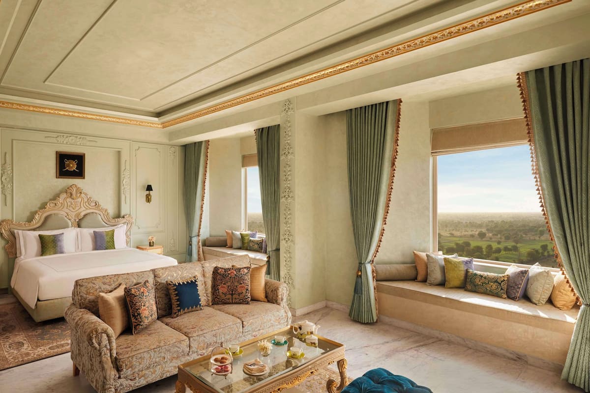Um quarto luxuoso com uma cama grande, um sofá, uma mesa de centro e vista para o campo.