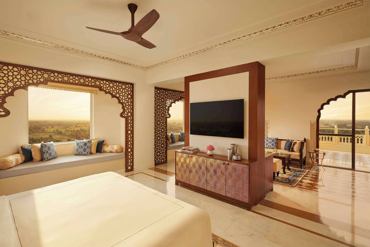 Quarto de hotel com cama, televisão, varanda e vista, além de detalhes decorativos.