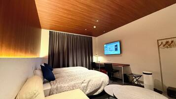 Quarto de hotel moderno com duas camas, uma escrivaninha, televisão e uma mesinha.
