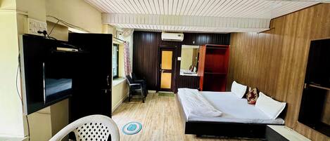 Quarto de hotel com cama, escrivaninha, cadeira, guarda-roupa e ar condicionado.