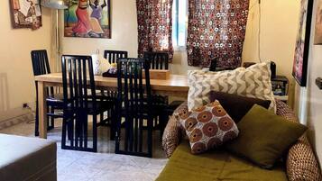 Uma sala de estar aconchegante com um sofá, uma mesa de jantar com cadeiras e um quadro na parede.