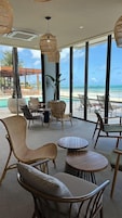 Ampla área de estar ao ar livre com móveis de vime e vista para a praia.