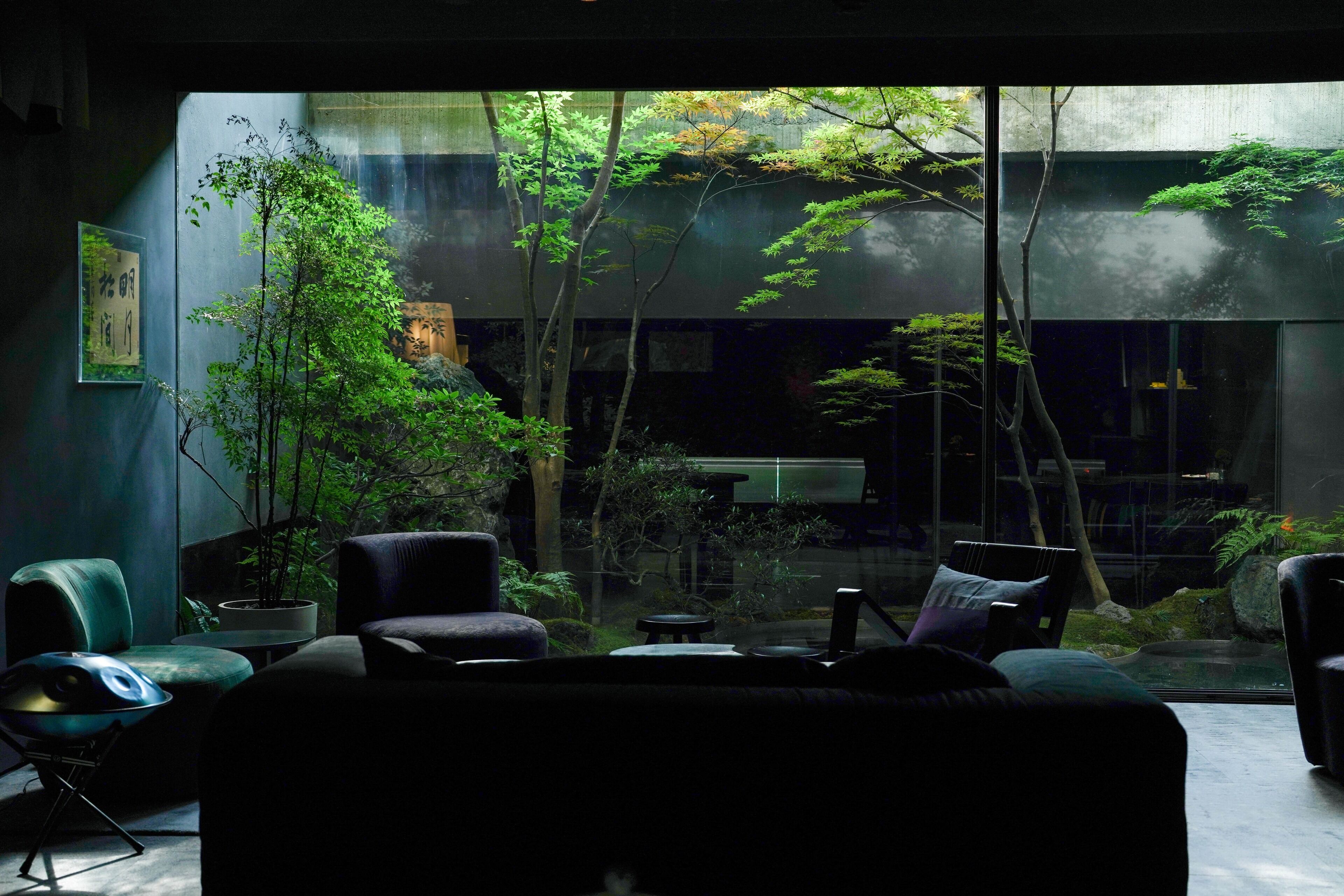 Um interior moderno com uma janela grande que dá para um jardim, assentos confortáveis e design minimalista.