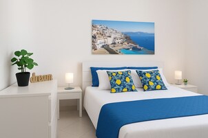 Quarto com cama, mesa de cabeceira, planta em vaso, quadro na parede e criadeira com abajur.