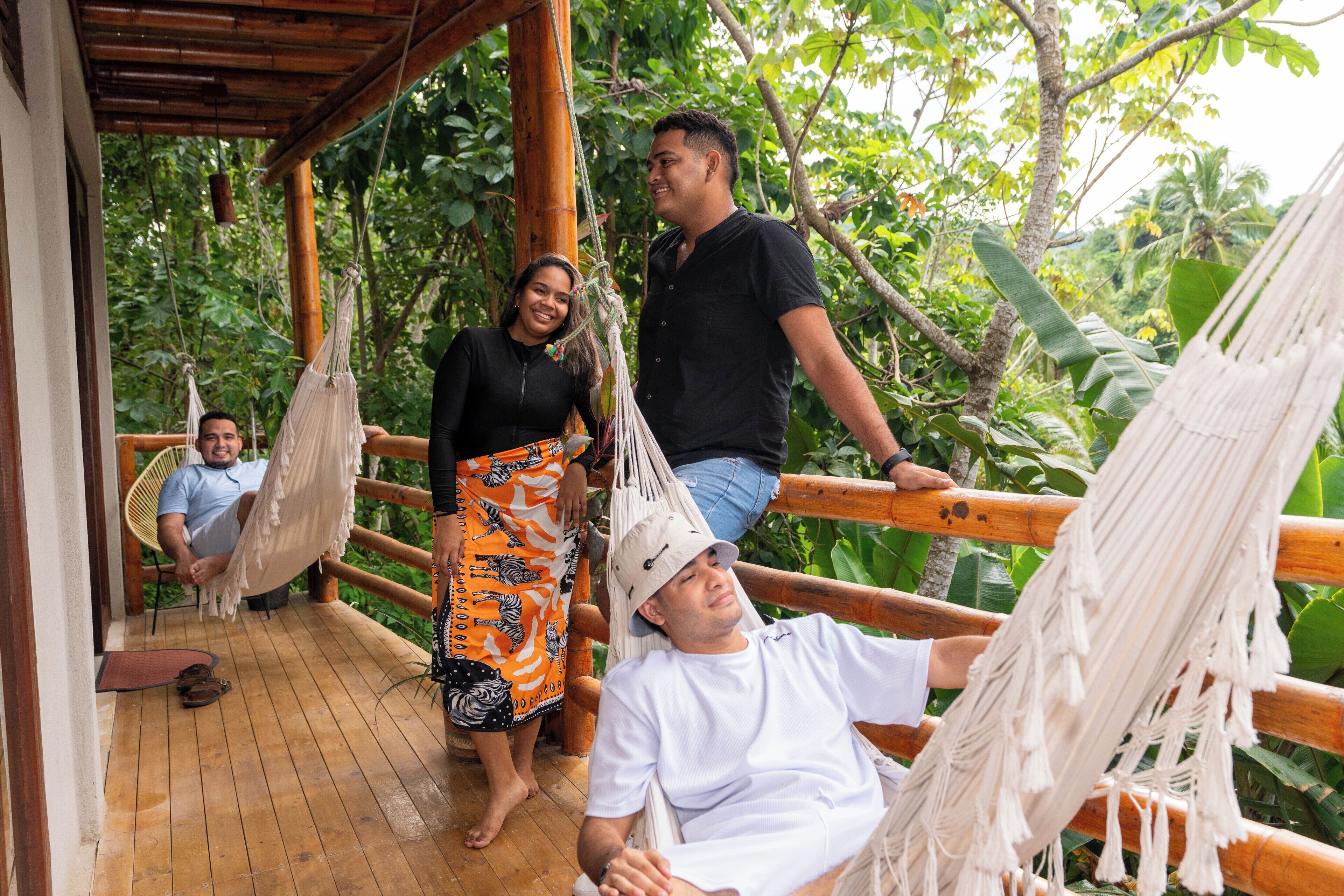 Um deck de madeira com redes e uma pessoa relaxando em uma rede.