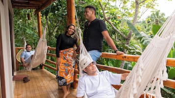 Um deck de madeira com redes e uma pessoa relaxando em uma rede.