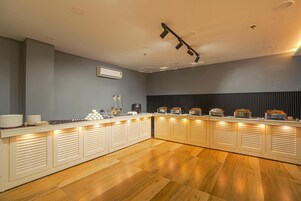 Um balcão de pequeno-almoço moderno com estação de café integrada, ar condicionado fixado na parede e chão em madeira.