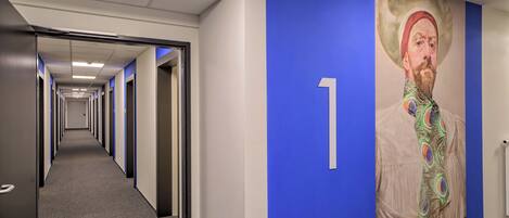 Um corredor com uma parede azul decorativa, uma placa com o número 1 e um padrão de pena de pavão na parede.
