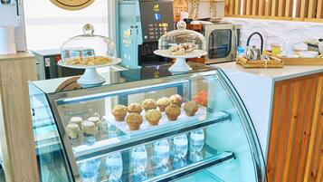 Um café com uma vitrine de vidro repleta de doces e uma máquina de café.