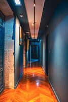 Um corredor com piso de madeira, parede de pedra e luminária no teto.