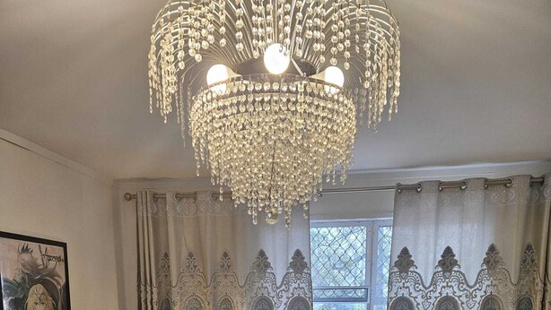 Quarto com uma cama grande, cortinas elaboradas, um candelabro e um quadro na parede.
