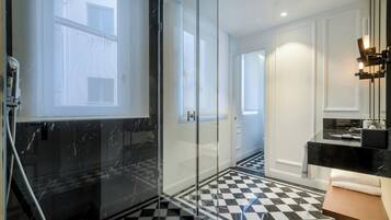 Um banheiro moderno com box de vidro, piso xadrez preto e branco e bancada de mármore preto.