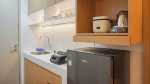 Uma cozinha compacta com geladeira de aço inoxidável, pia e armários de madeira.