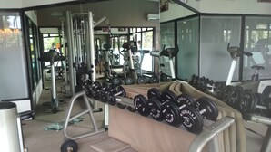Uma academia com diversos equipamentos de exercícios, incluindo halteres e esteira.