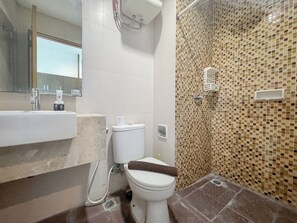 Casa de banho com sanita, lavatório e área de duche.