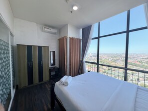 Quarto de hotel com cama, guarda-roupa, espelho e janela com vista para a cidade.