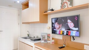 Cozinha moderna com televisão integrada, armários de madeira, uma pia e bancada com controle remoto.