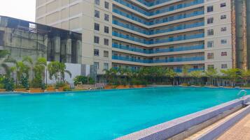 Um hotel com uma piscina grande, várias varandas e vegetação ao redor.
