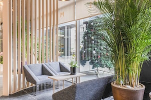 Um espaço interior moderno com área de estar, incluindo dois sofás cinzentos, uma mesinha e uma grande planta em vaso.