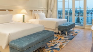 Quarto de hotel com duas camas, uma janela grande com vista e uma varanda.