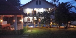 Um edifício de dois andares com varanda, piscina e área de estar coberta ao ar livre.
