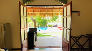 Abertura de porta que dá para uma área de piscina, com vista para a piscina, uma árvore e móveis de exterior.
