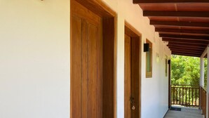 Corredor com portas de madeira e varanda com guarda-corpo de metal.