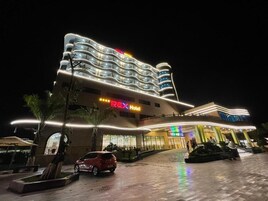 Um hotel moderno com fachada curva, várias varandas e entrada bem iluminada.